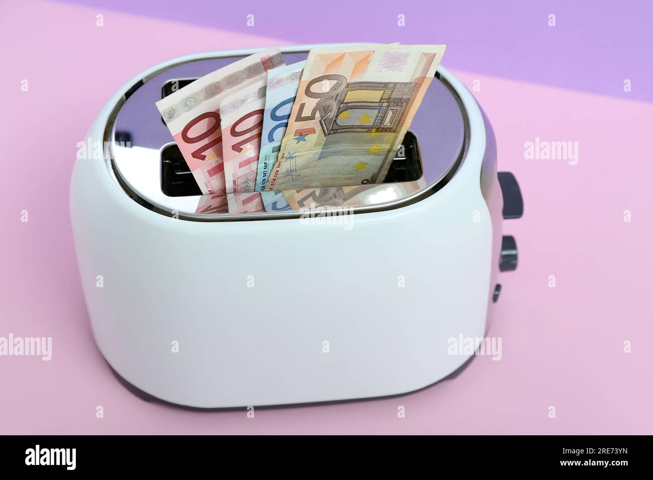 Toaster with euro banknotes on table near lilac wall Stock Photo - Alamy