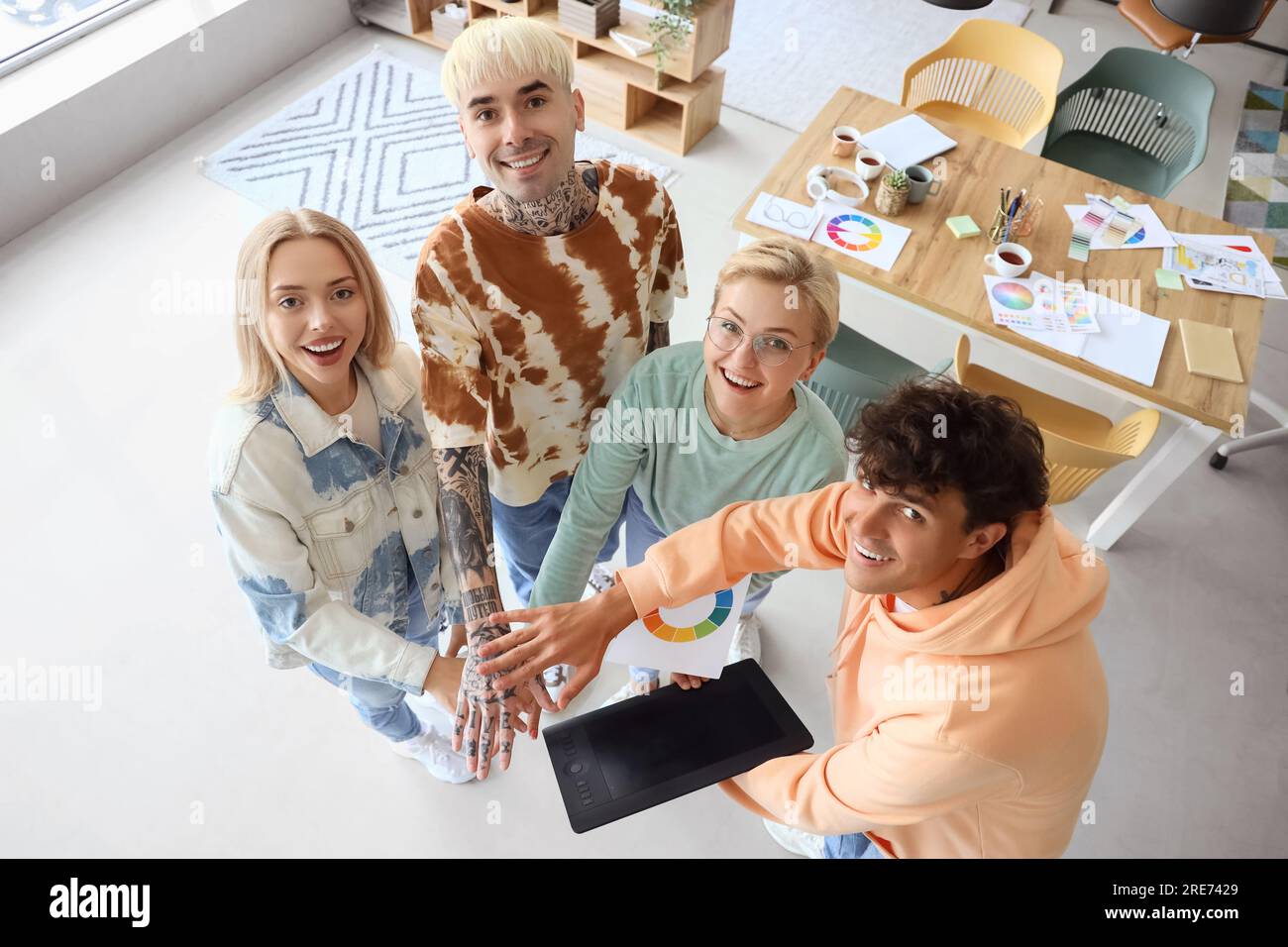 Team of graphic designers putting hands together in office Stock Photo ...