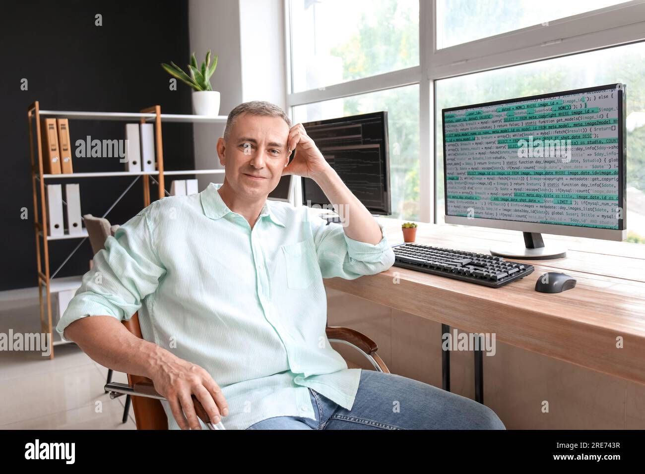 Mature male programmer sitting in light office at his workplace Stock ...