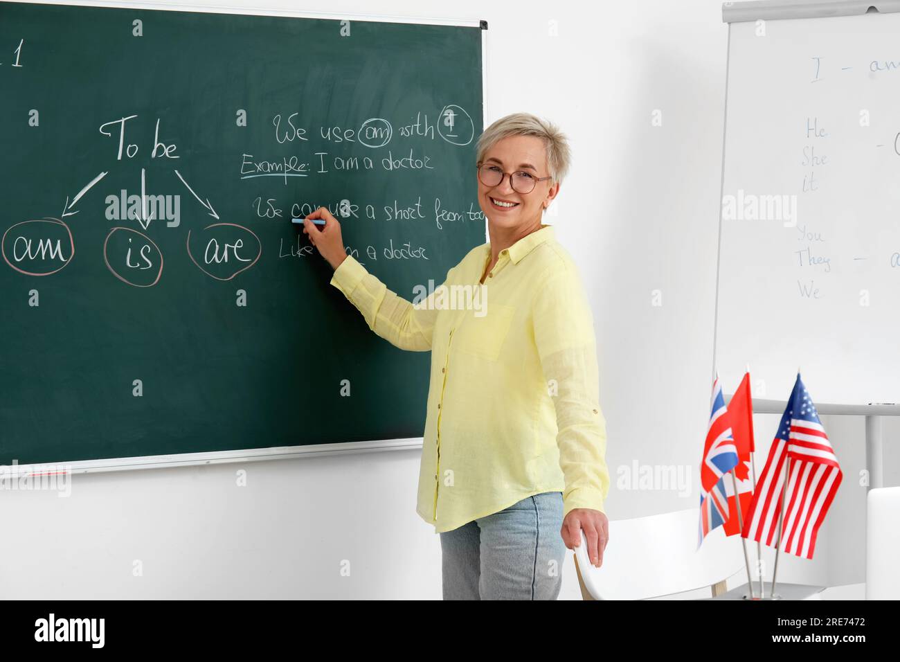 Female teacher writing English grammar on chalkboard in classroom Stock ...