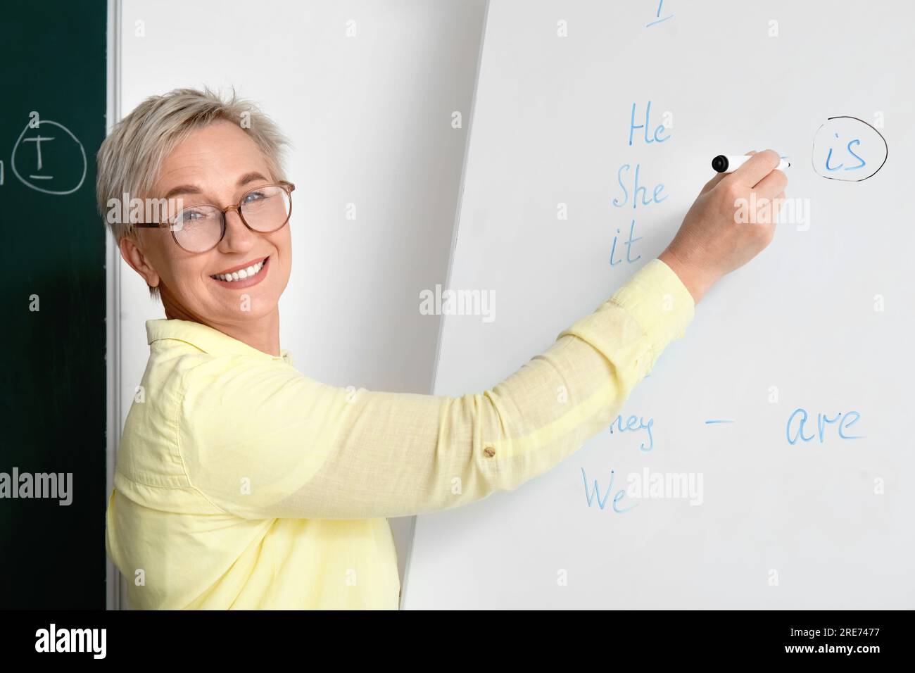Female teacher writing English grammar on flipboard in classroom Stock ...