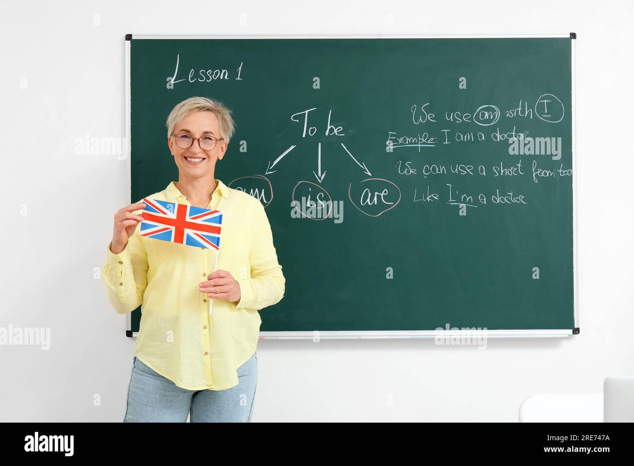 Female English teacher with UK flag in classroom Stock Photo - Alamy