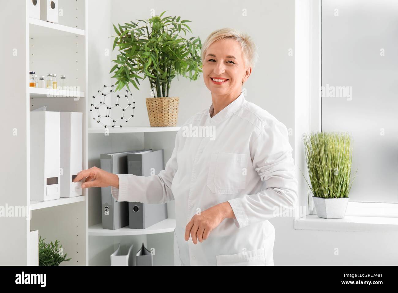 Female doctor taking folder from shelf in clinic Stock Photo - Alamy