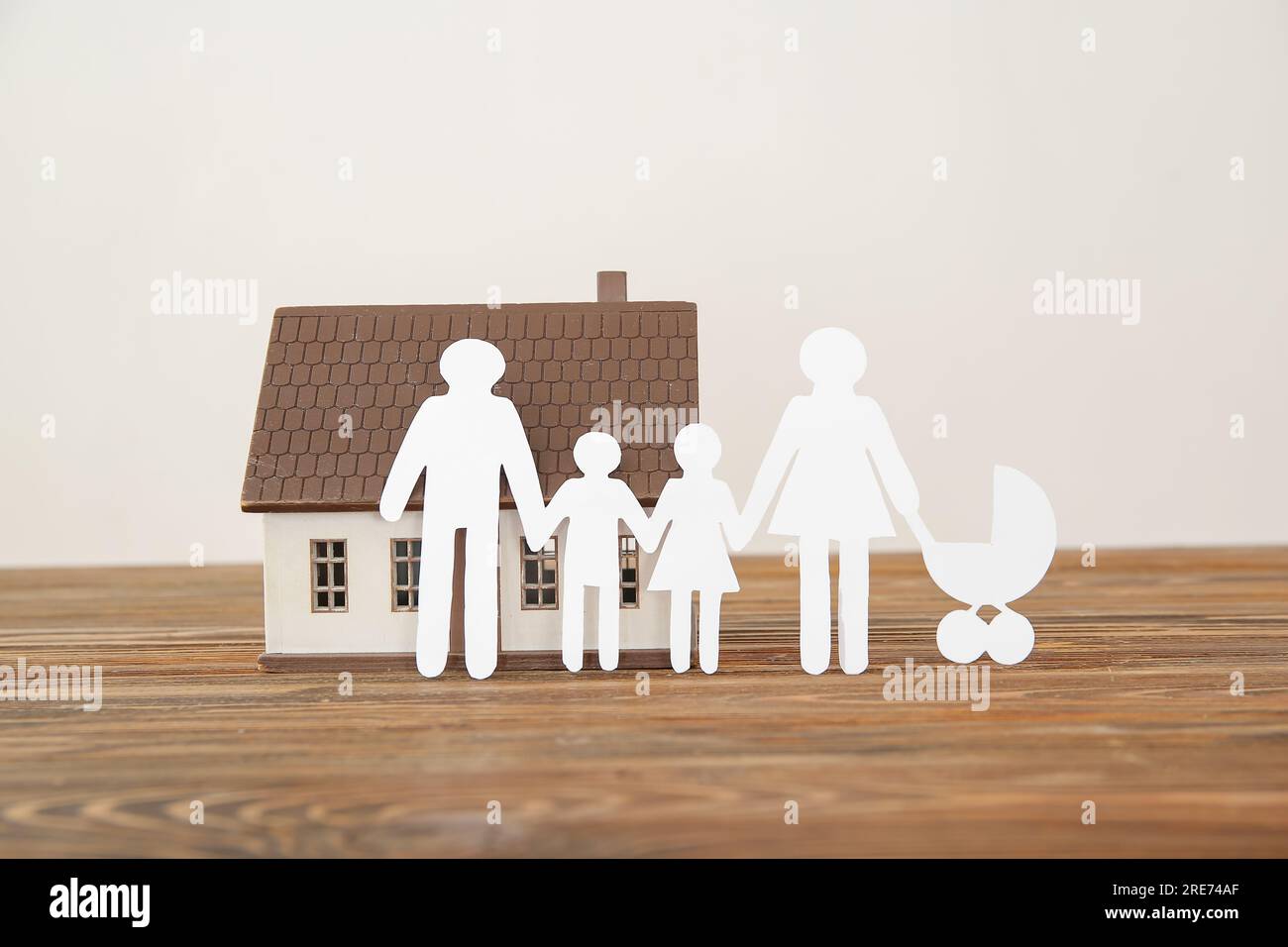 Figures of family with house on brown wooden table Stock Photo - Alamy
