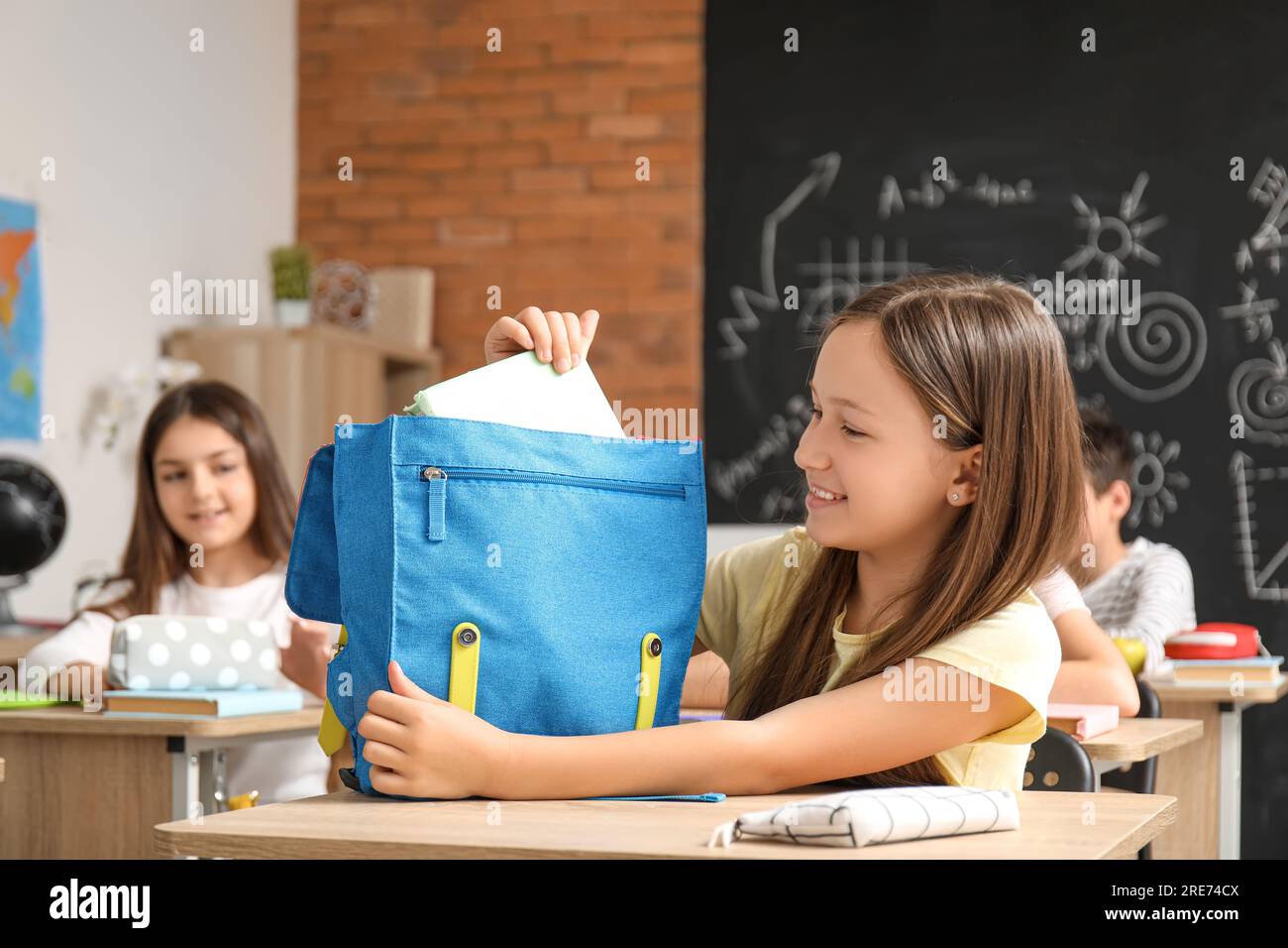 Little girl with backpack in classroom Stock Photo - Alamy