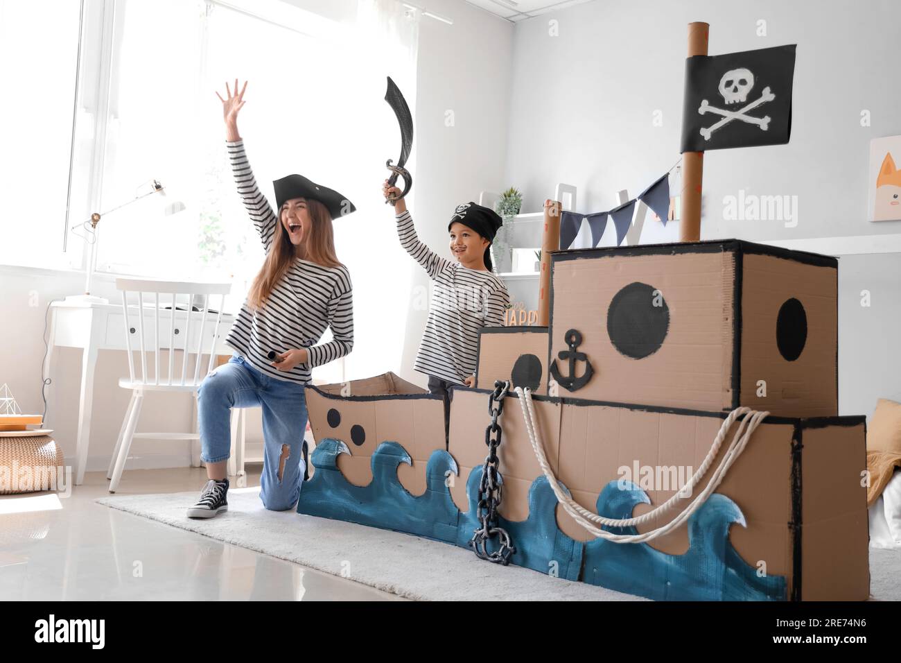Cute little boy with his mother dressed as pirates playing at home ...