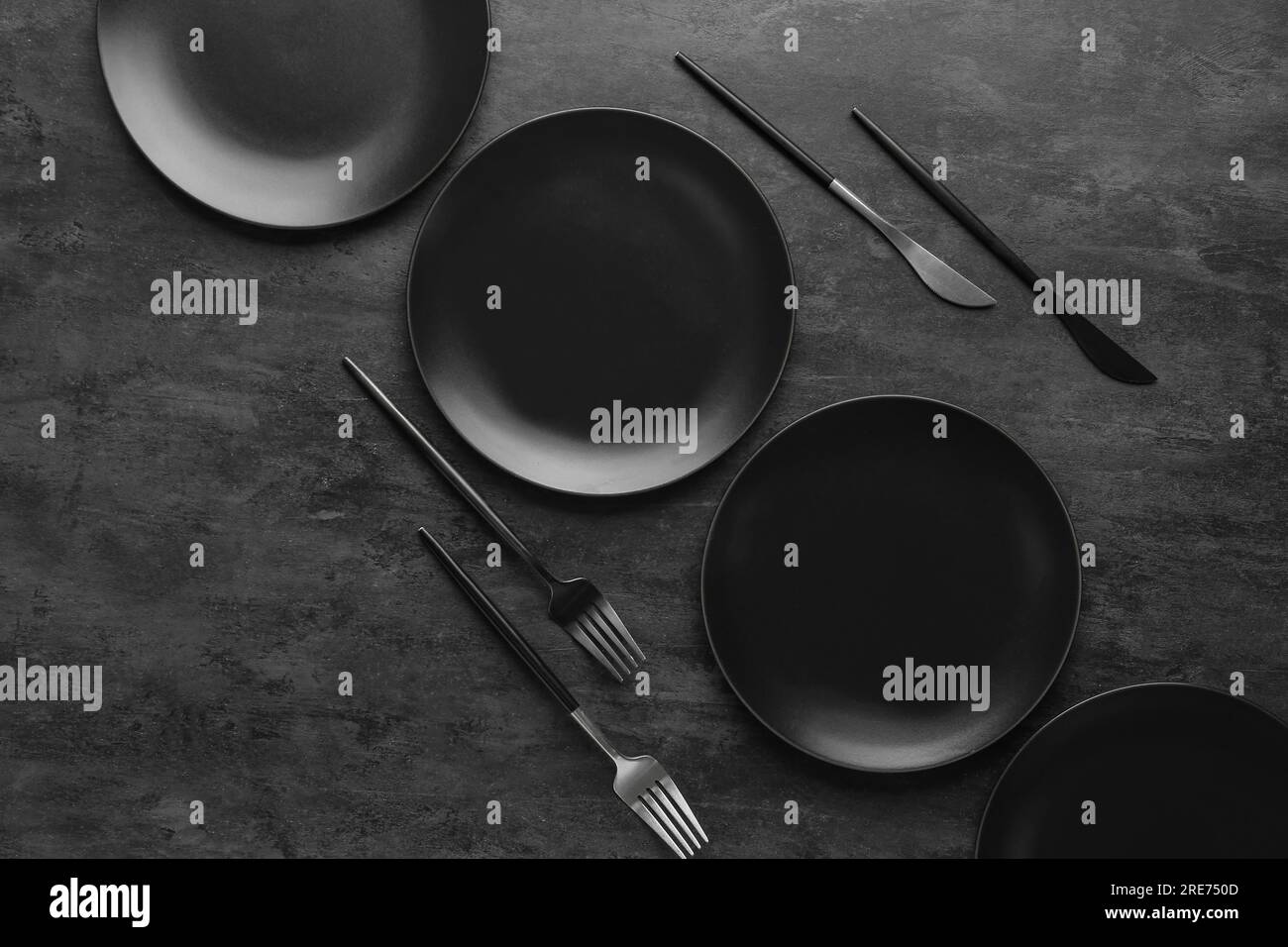 Set of clean plates and cutlery on black grunge table Stock Photo - Alamy