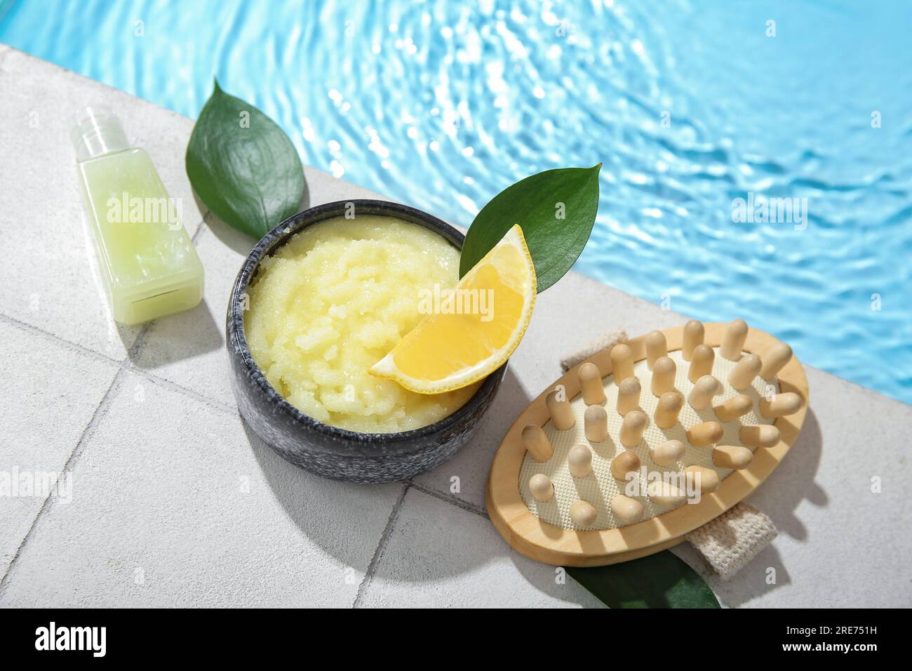 Lemon body scrub with massage brush and cosmetic bottle on edge of ...