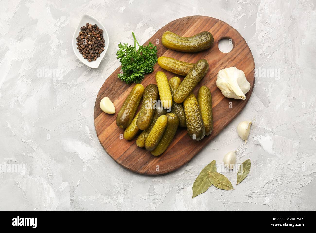 Wooden board with pickled cucumbers and different spices on grey ...