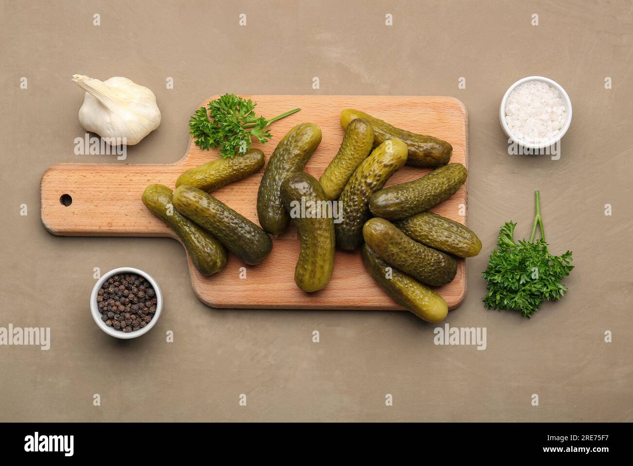 Wooden board with pickled cucumbers and different spices on brown ...