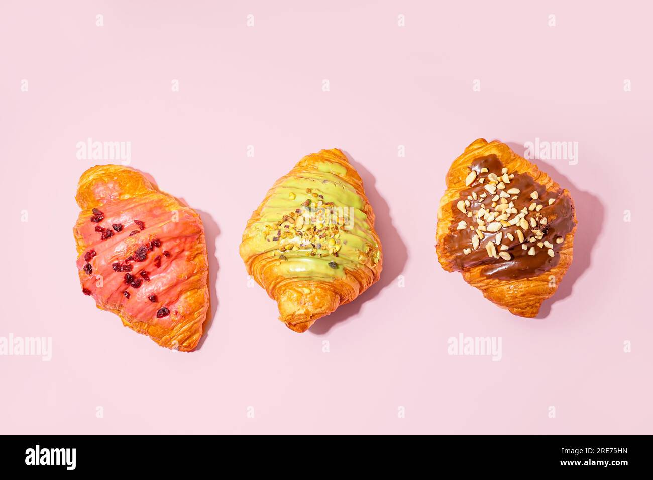 Different sweet croissants on pink background Stock Photo - Alamy