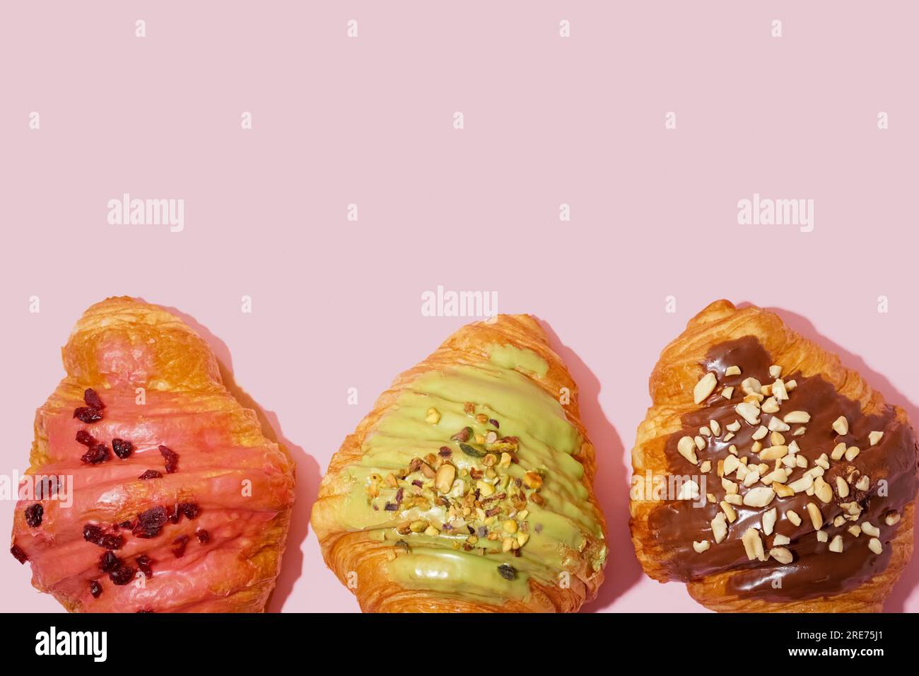 Different sweet croissants on pink background Stock Photo - Alamy