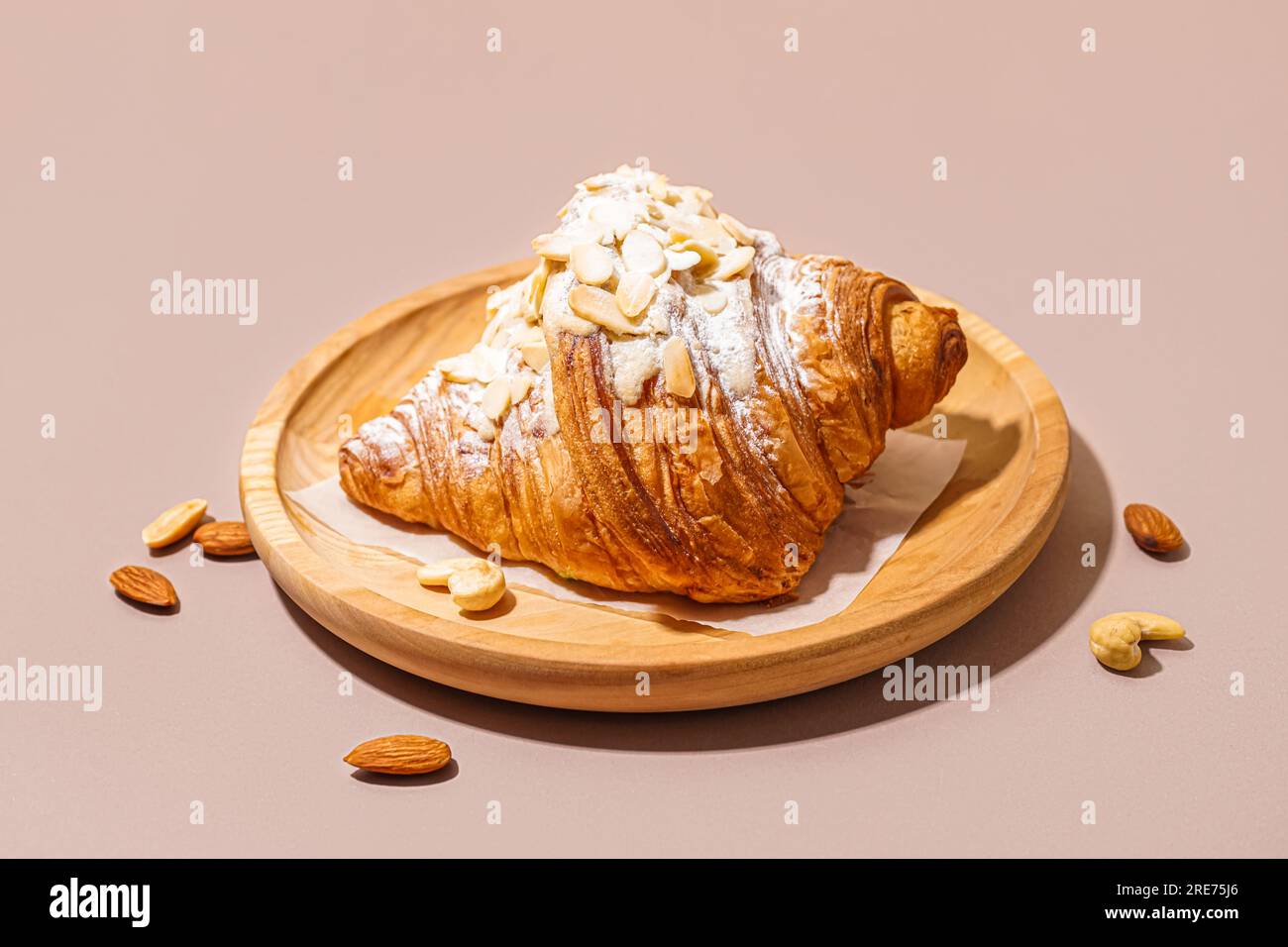 Wooden plate of sweet croissant with powdered sugar and different nuts ...