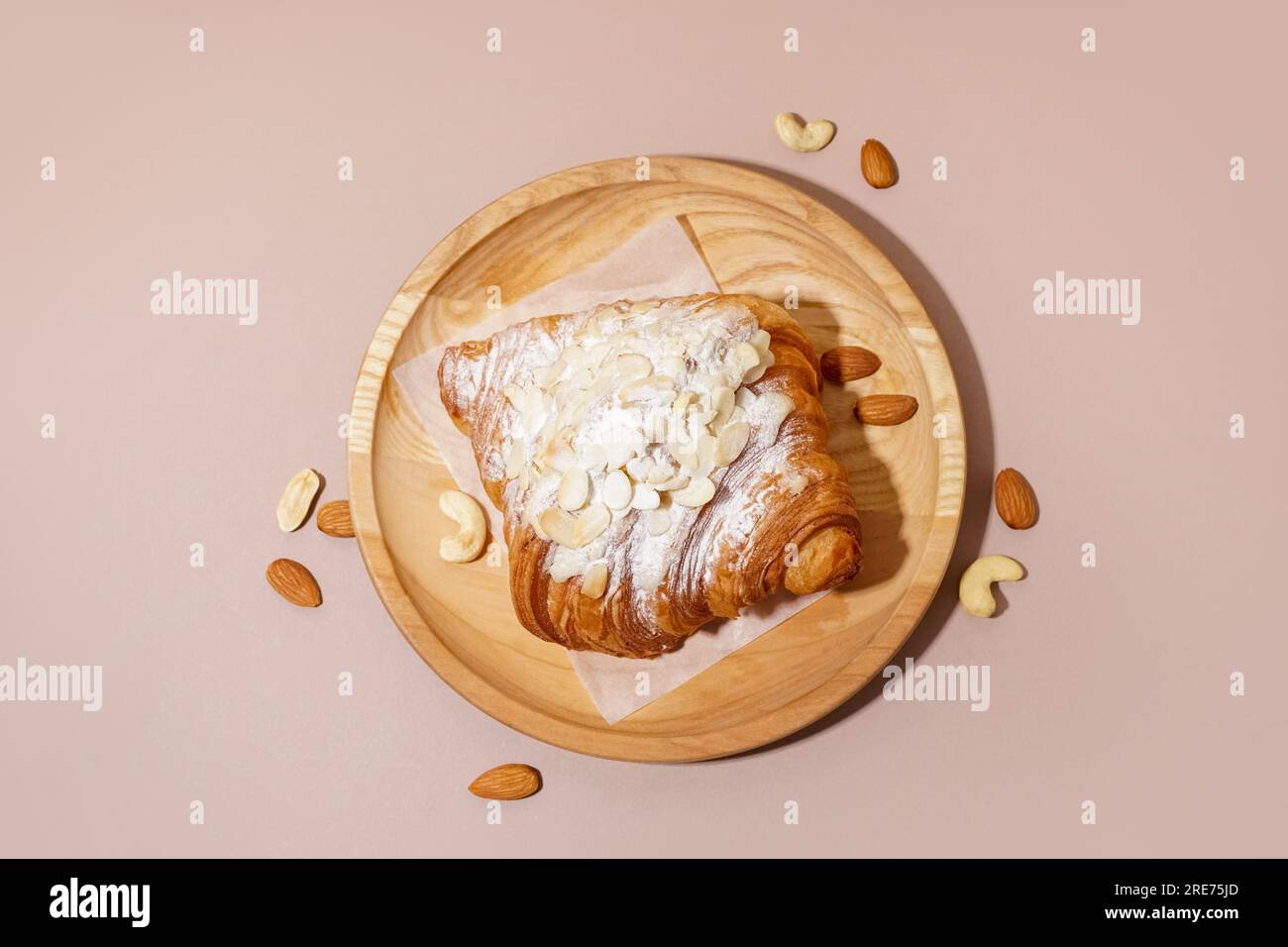 Wooden plate of sweet croissant with powdered sugar and different nuts ...