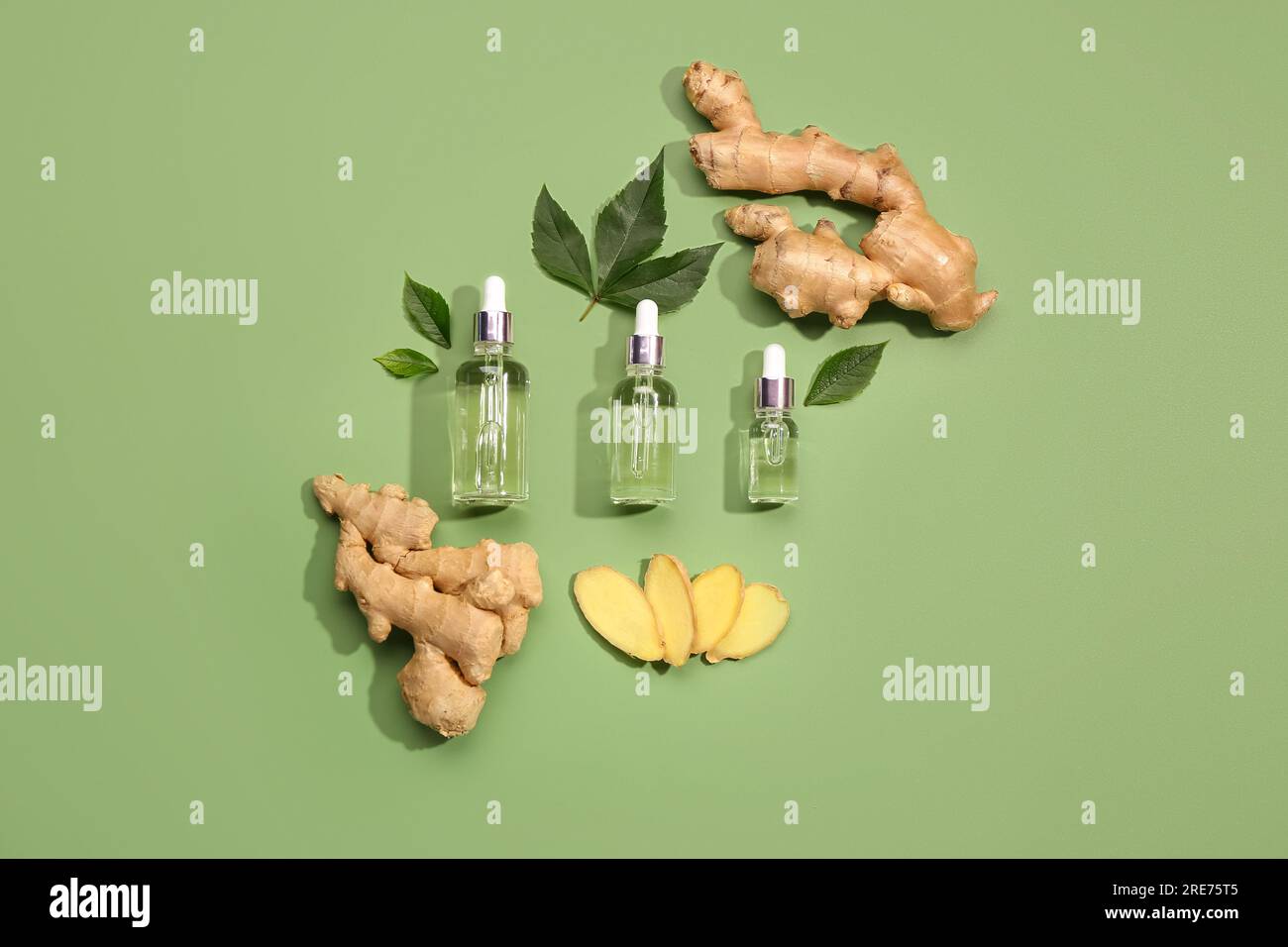 Bottles of ginger cosmetic oil and leaves on green background Stock ...