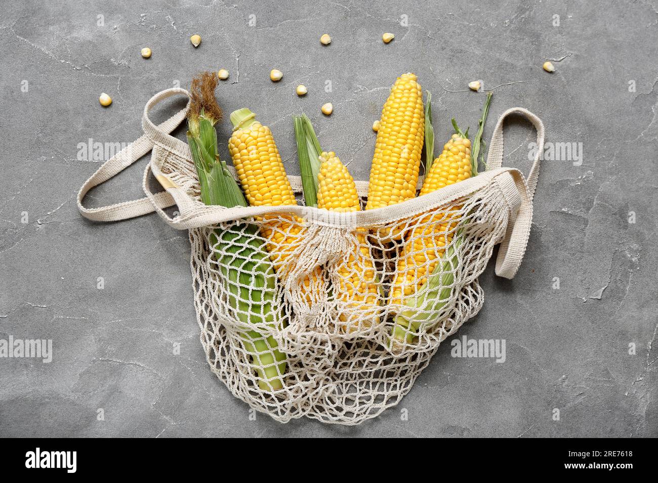 Mesh bag with fresh corn cobs on grey table Stock Photo - Alamy