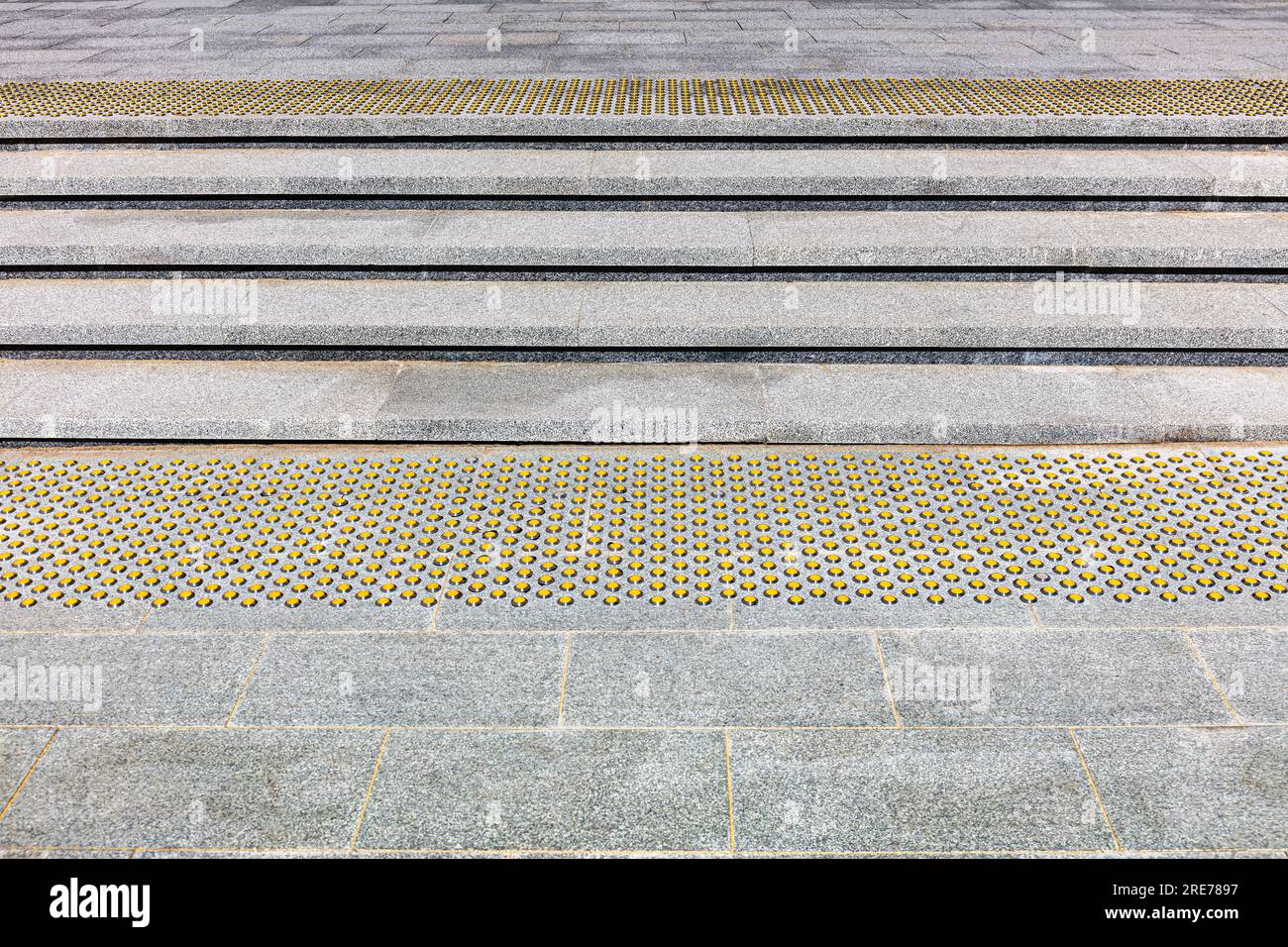 wide modern stone staircase with yellow nonskid tactile paving for a ...