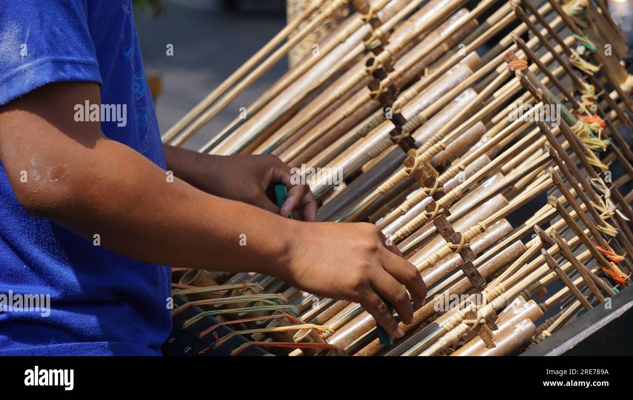 A man is playing angklung. That is a multitonal musical instrument that ...