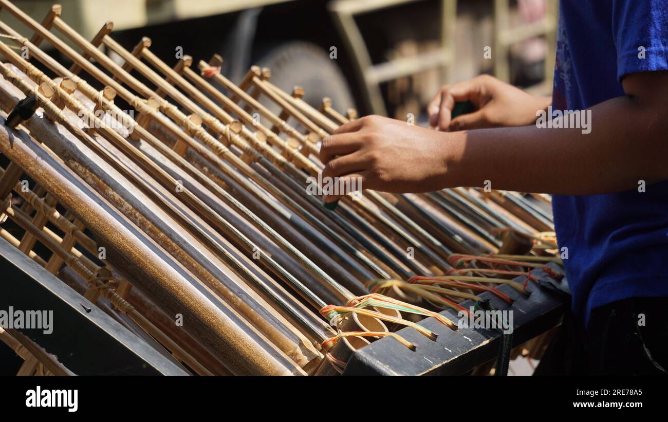 A man is playing angklung. That is a multitonal musical instrument that ...