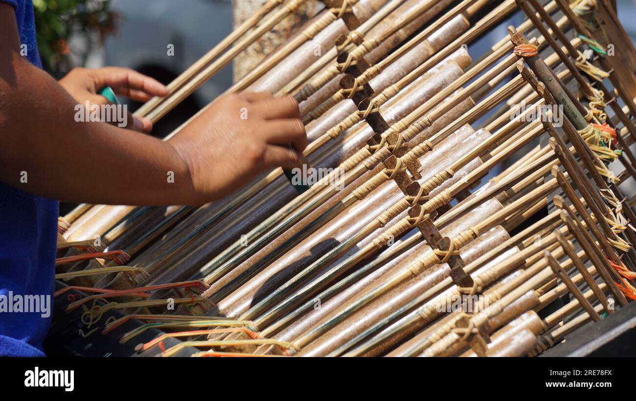 A man is playing angklung. That is a multitonal musical instrument that ...