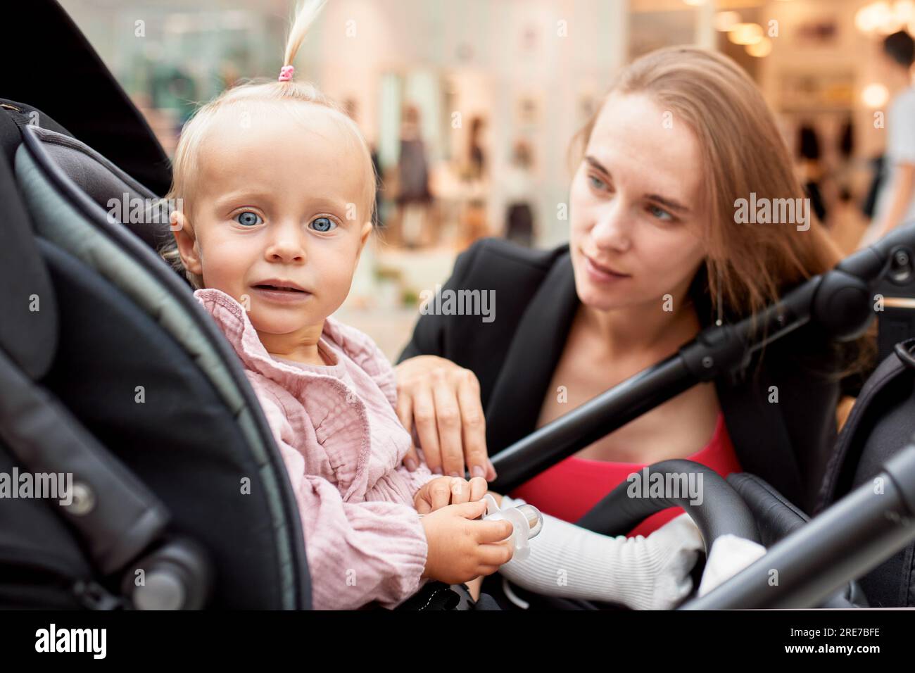 Close-up portrait of a small child in a carriage, blonde baby girl in ...