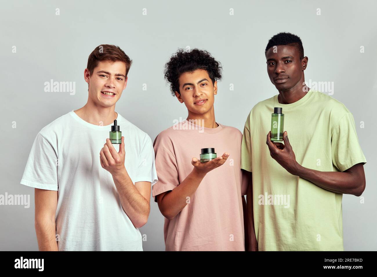 Three young handsome men of different races with cosmetic products in ...