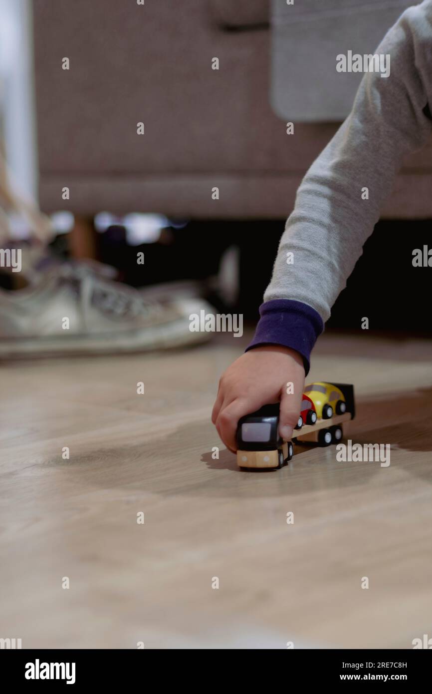 Kid hand playing with wooden truck on an indoor scene with a hardwood ...