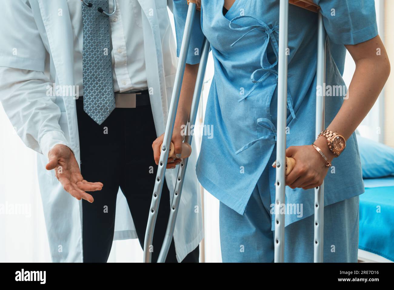 Doctor takes care of patient in crutch at hospital. Physical therapist ...