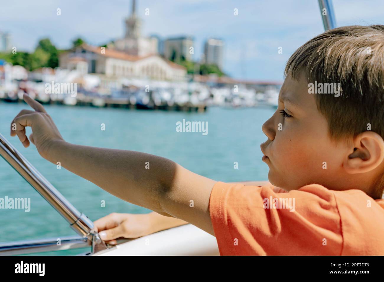 boy sailing on yacht enjoying sea view pointing to sea port. Image with ...