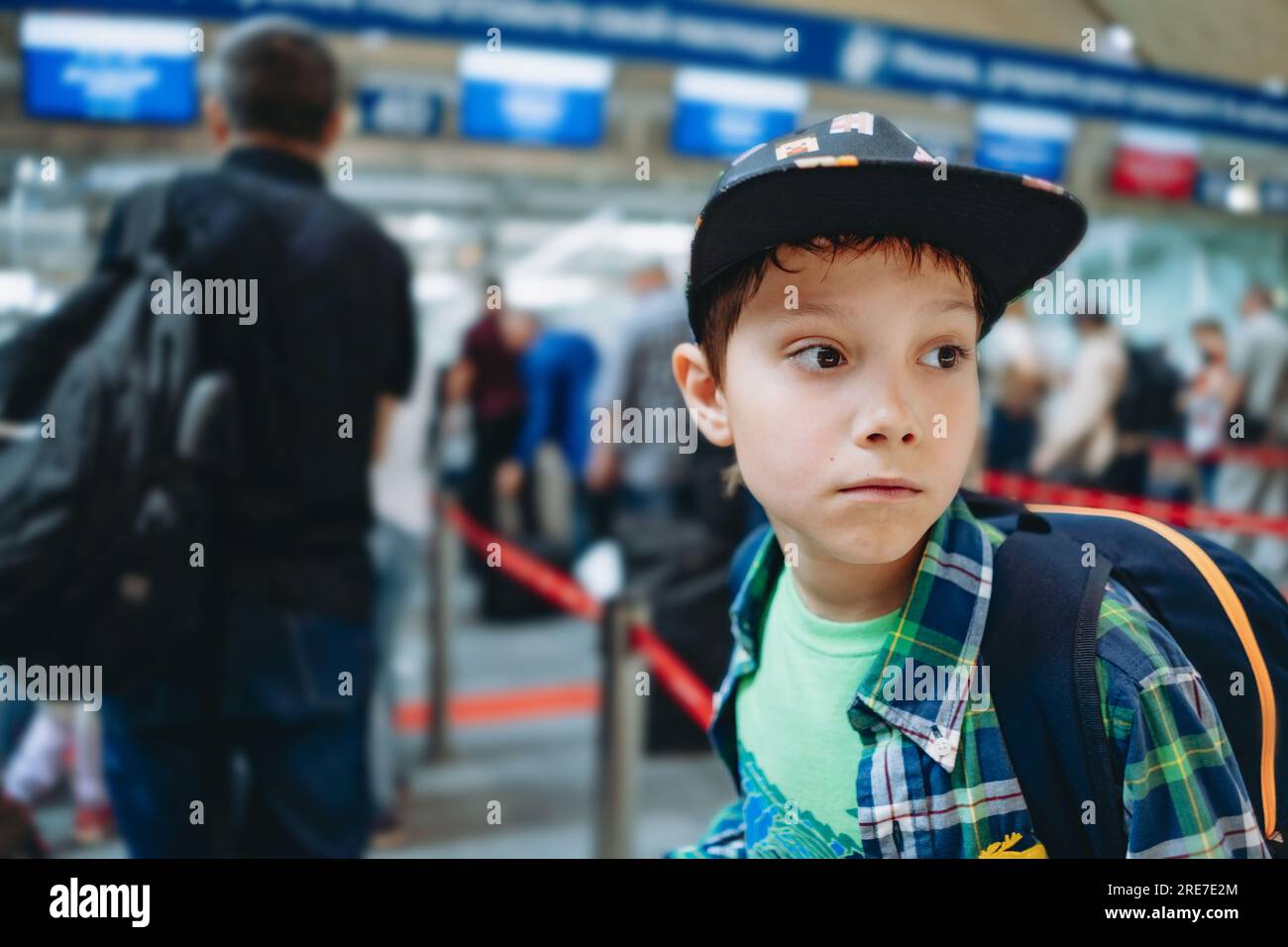 sad caucasian boy alone in airport with backpack and suitcase by check ...