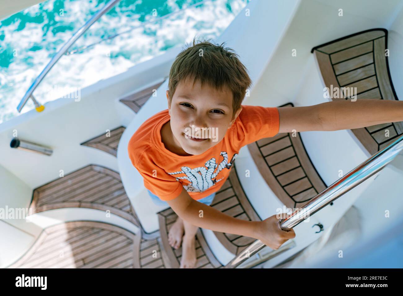 Handsome caucasian boy sailing on yacht going down the stairs from deck ...