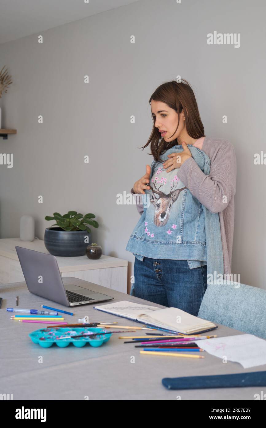 Caucasian woman streaming showing her art design in a denim jacket ...