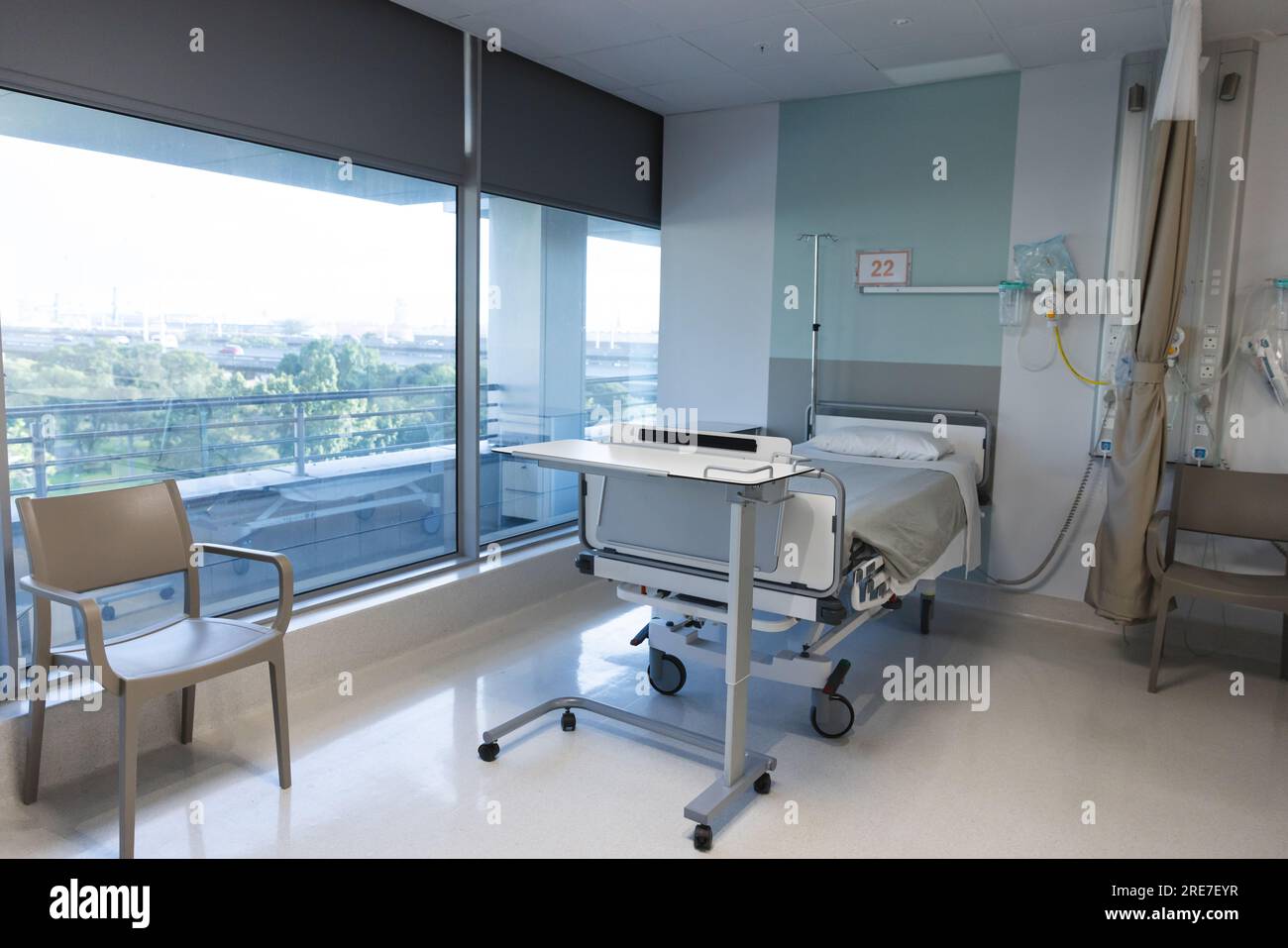 General view of patient room with bed, medical equipment and windows at ...