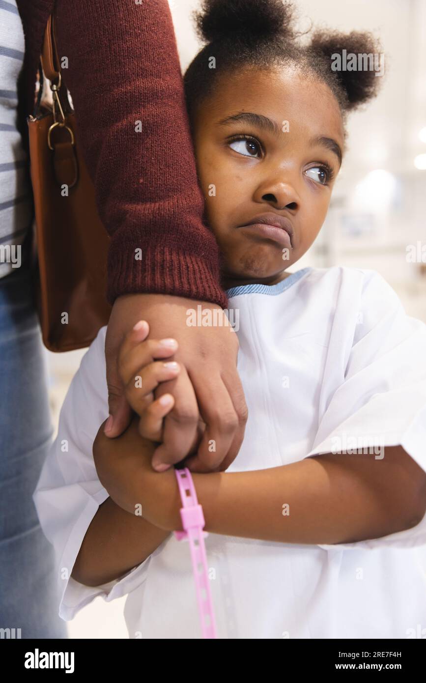 Sad African American Girl Patient And Her Mother Holding Hands In Corridor At Hospital Stock