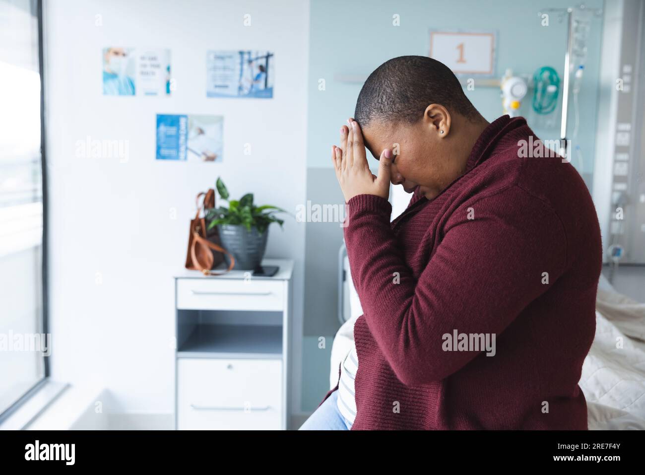 Sad african american female patient sitting on bed and crying in ...