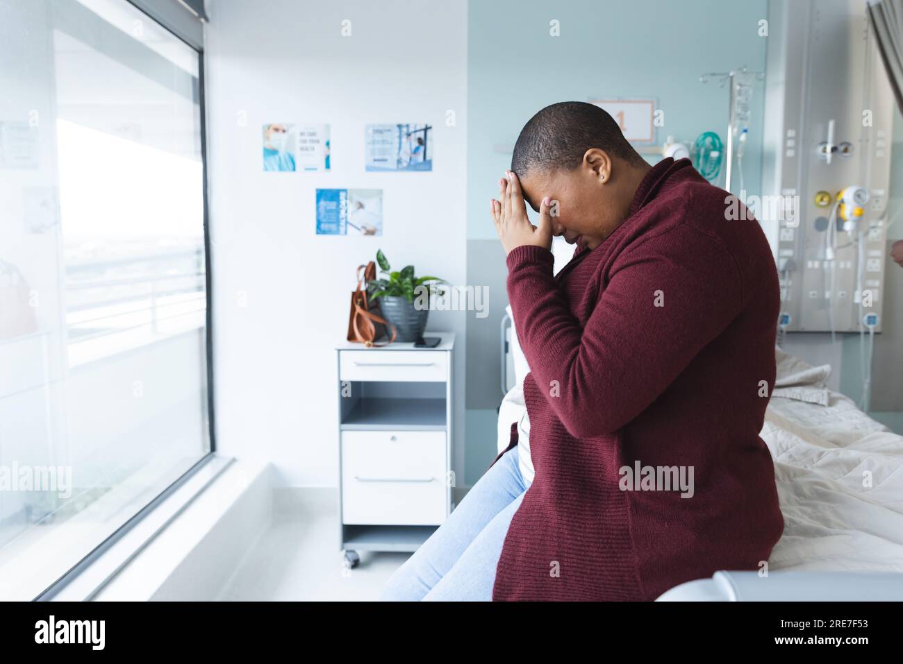 Sad african american female patient sitting on bed and crying in ...