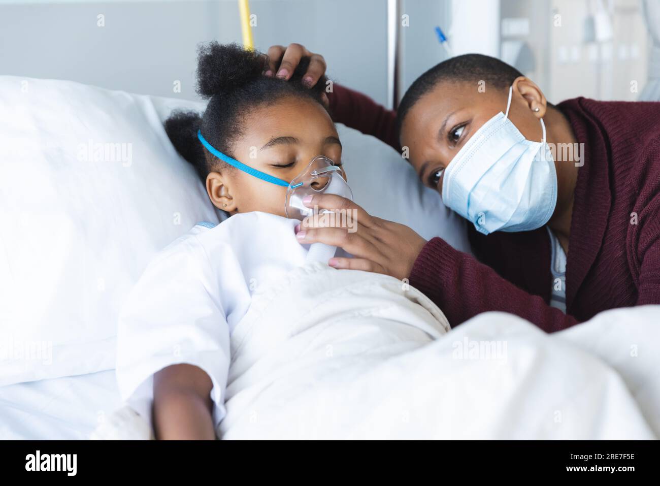 African american girl patient lying on bed with oxygen mask, with her ...