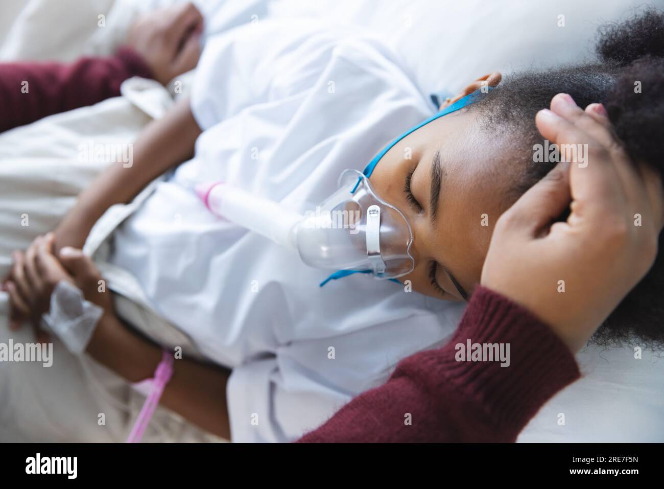 African american girl patient lying on bed with oxygen mask, with her ...