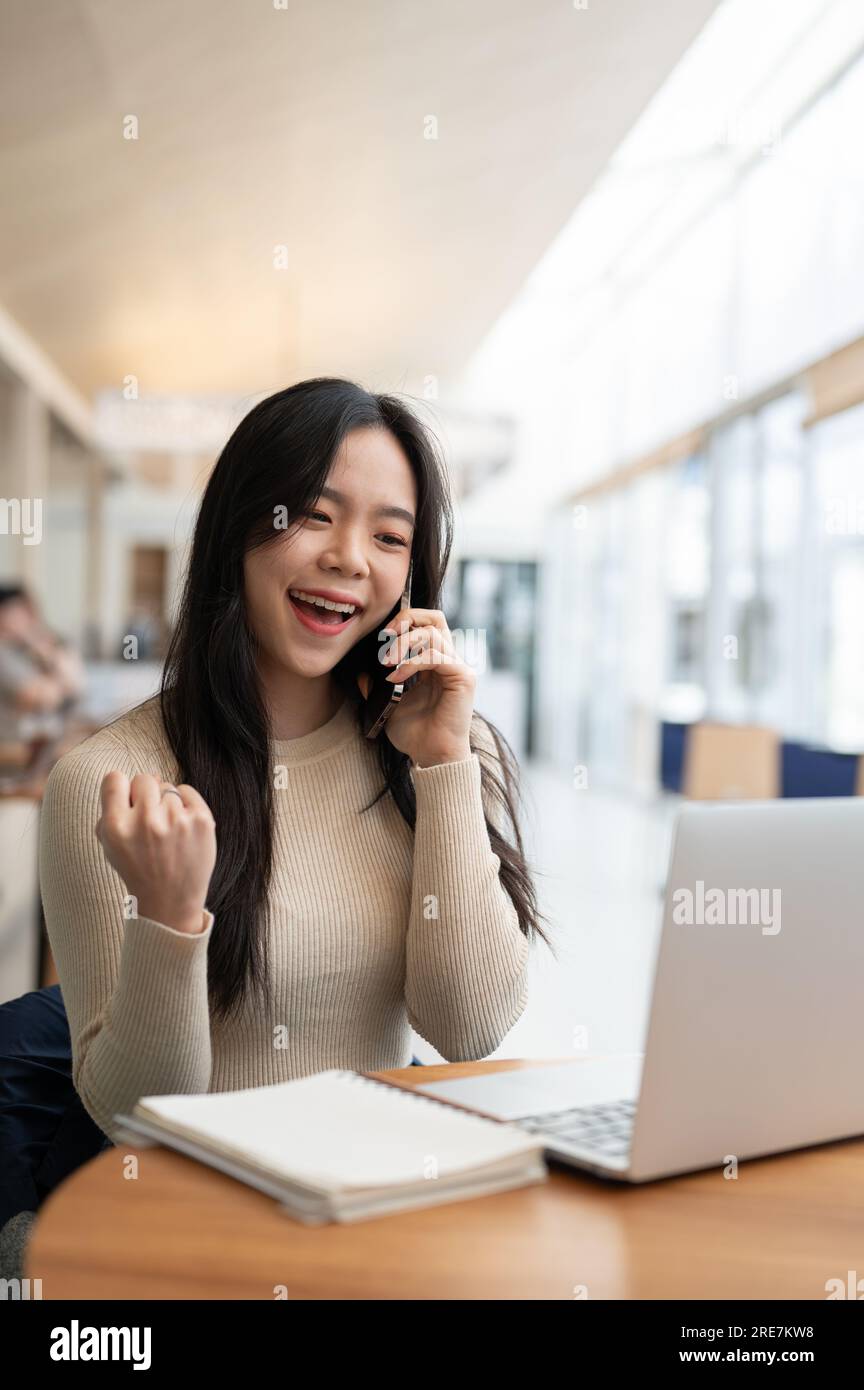 A portrait of a happy young Asian woman rejoicing after receiving good ...
