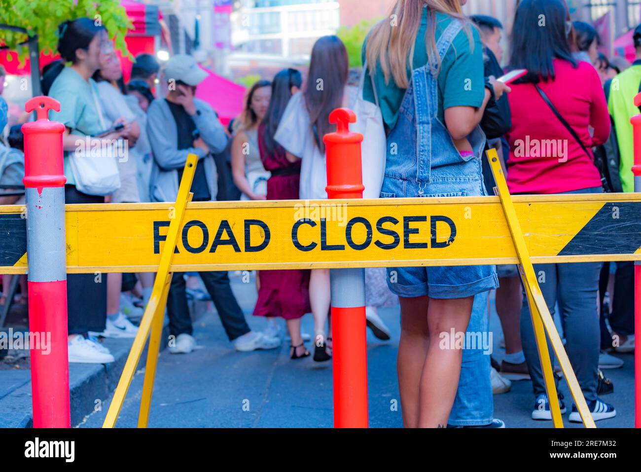 A crowd of people walking behind a Road Closed sign near Dixon Street ...