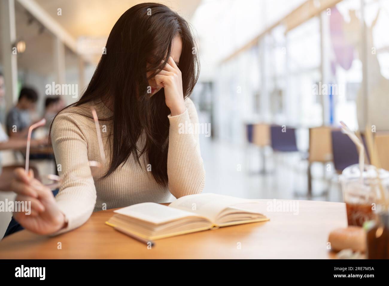 A tired and unhappy young Asian female college student suffering from ...