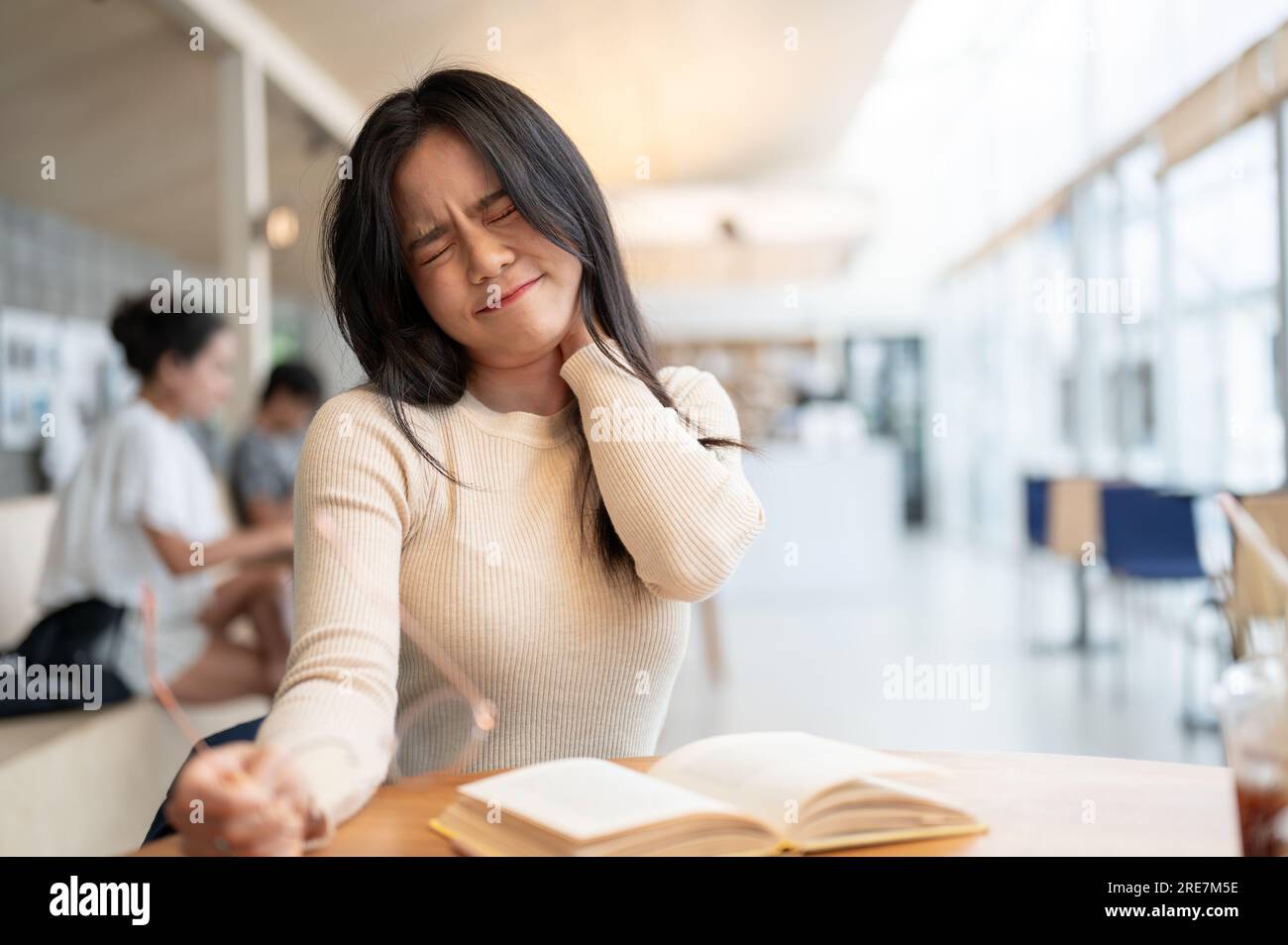 A tired and unhappy young Asian female college student suffering from a ...