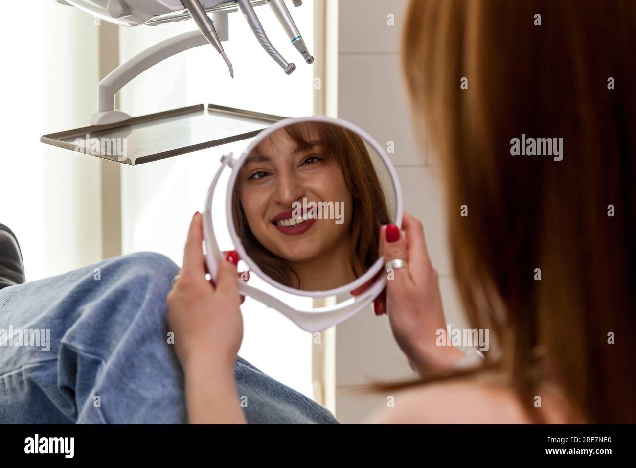 A beautiful girl smiles at her reflection in the mirror. A girl with ...