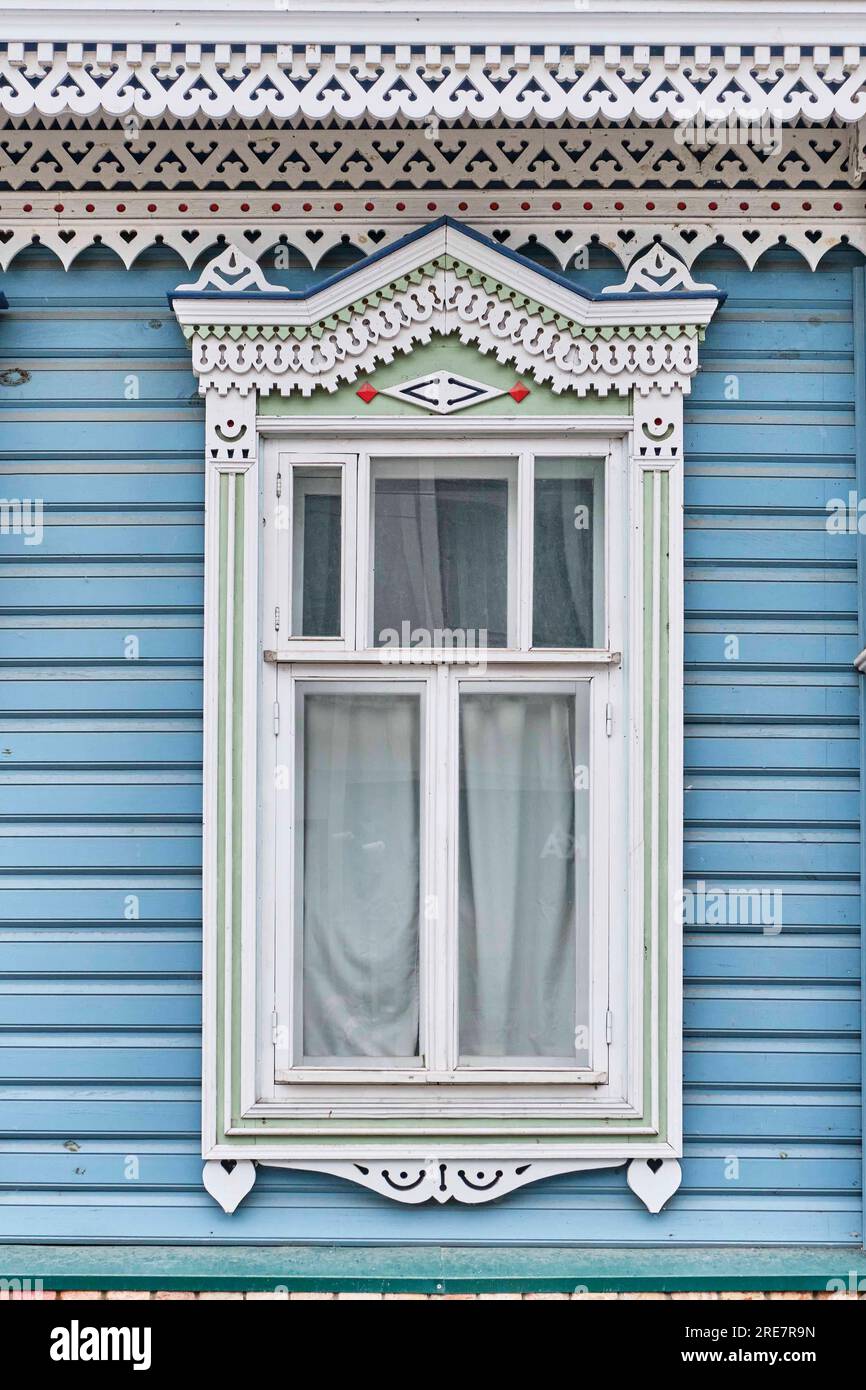 Typical wooden window with carved architraves on blue boardwalk facade ...