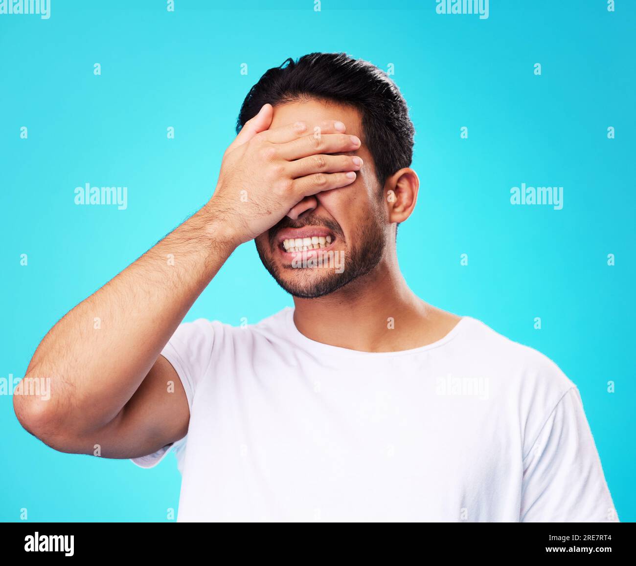 Scared, covering eyes and a man on a blue background for fear, anxiety ...