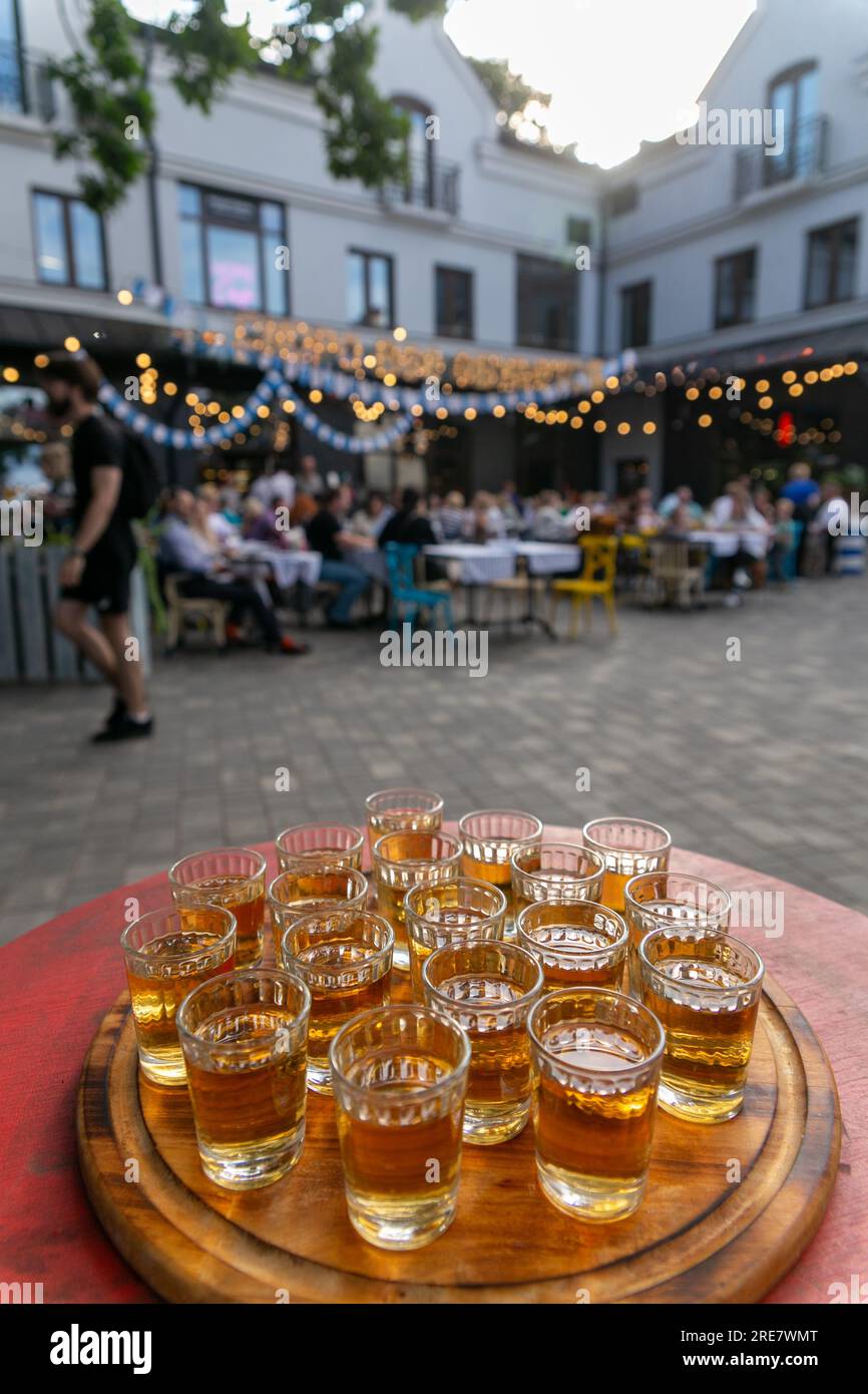 Small glasses filled with brandy on a wooden tray. Alcoholic buffet in ...