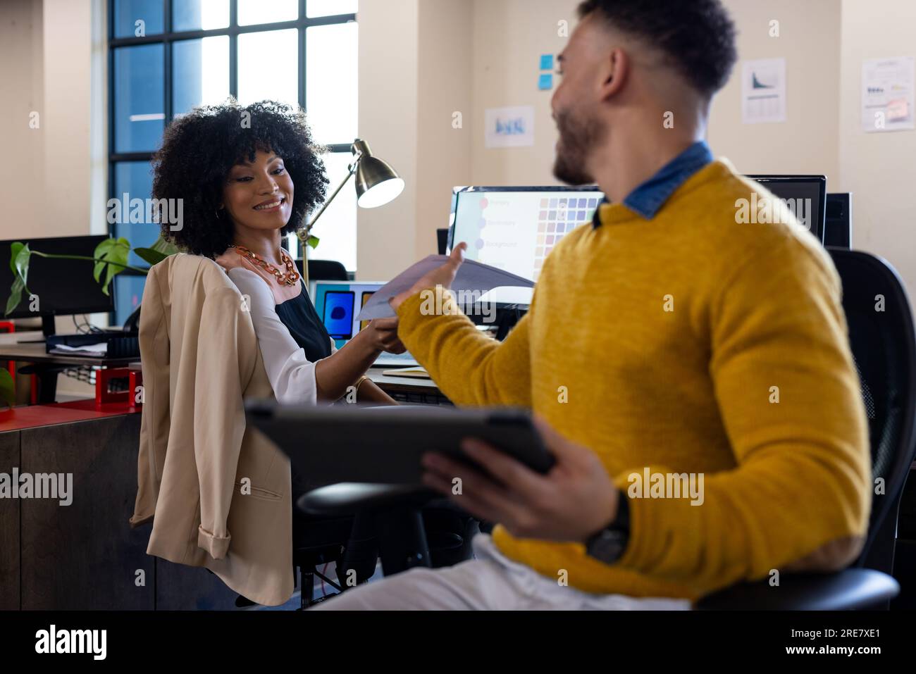 Diverse woman passing a document to a man at office Stock Photo - Alamy