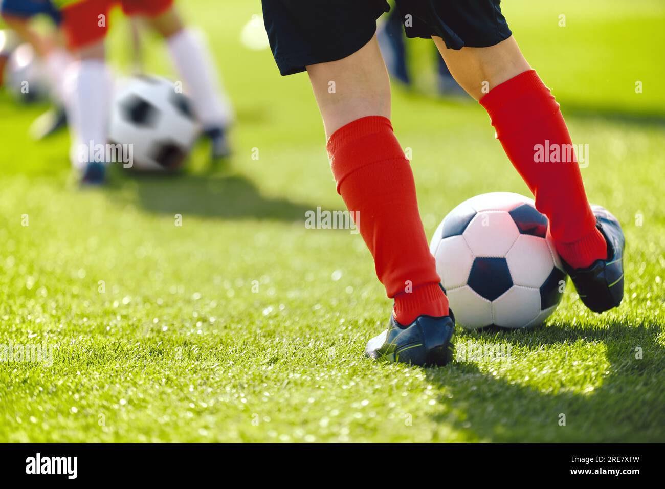 Close-up of legs and feet of football player in red socks and shoes ...