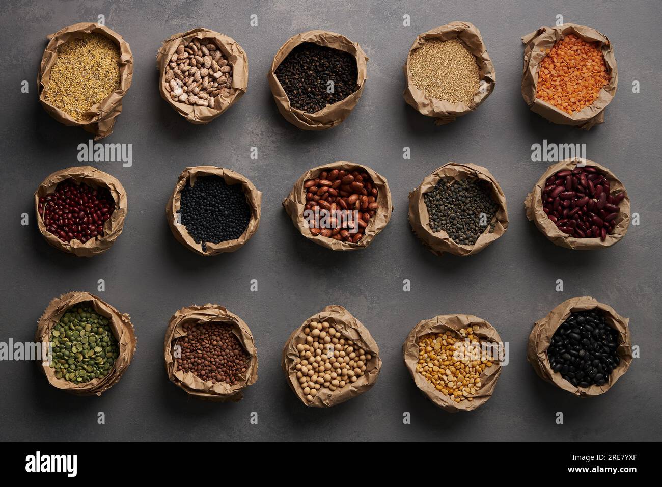 Various pulses, lentils, legumes and beans in brown paper bags on grey ...