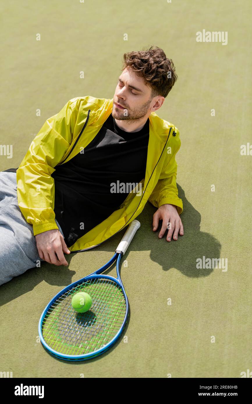 overhead shot, male tennis player on court, resting near tennis ball ...